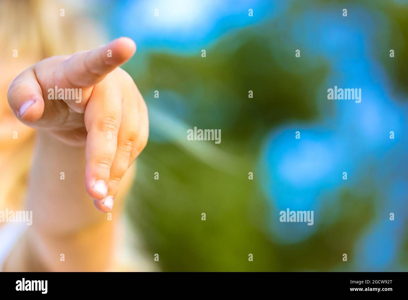 A little blonde infant girl pointing finger into a distance straight ...