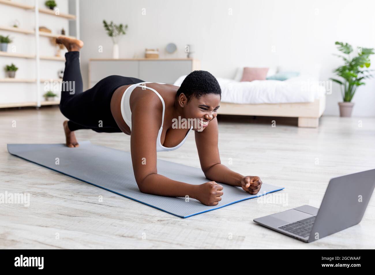 Plus size Afro lady working out at home with online personal trainer ...