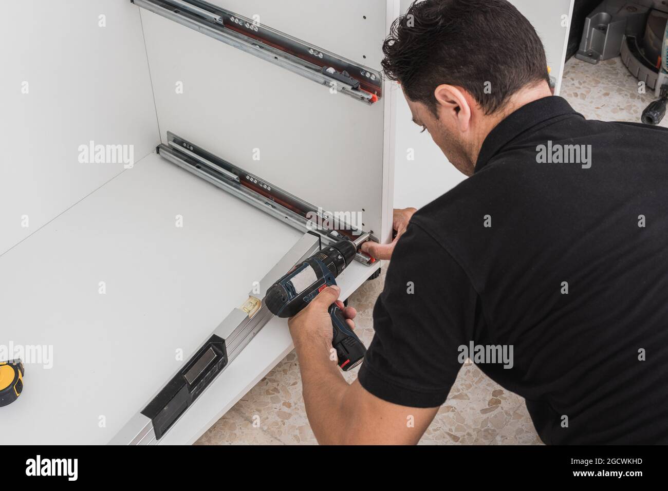 Man fixing kitchen cabinet rails with a drill Stock Photo - Alamy