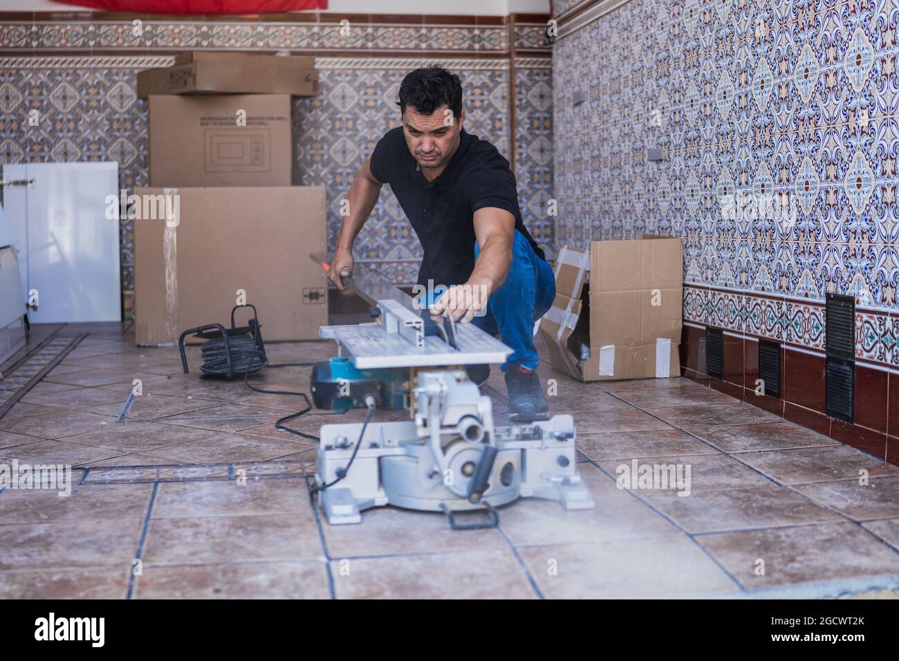 man cutting a panel with an electric machine to install a kitchen ...