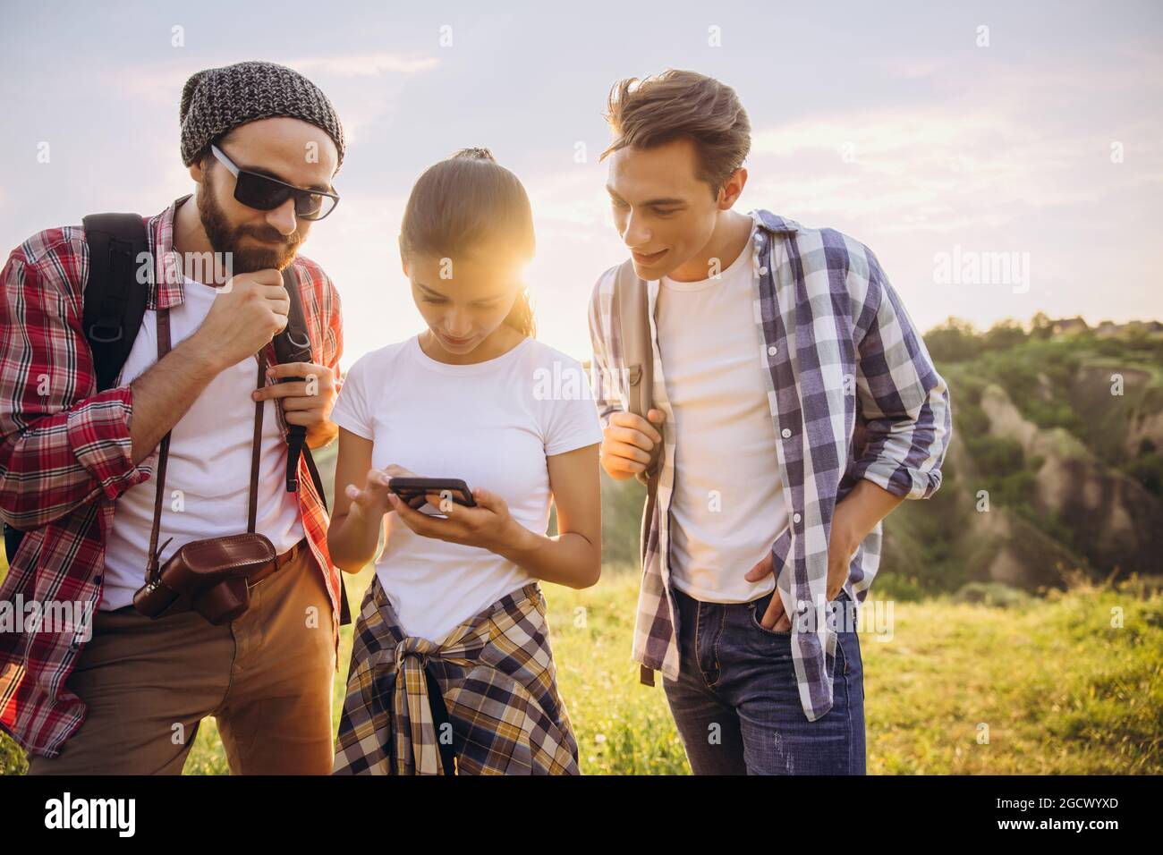 Group of friends, young men and woman walking, strolling together in summer forest, meadow ...