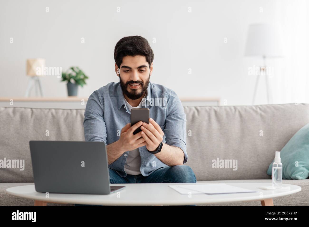 Business and telecommuting concept. Happy young arab man using ...