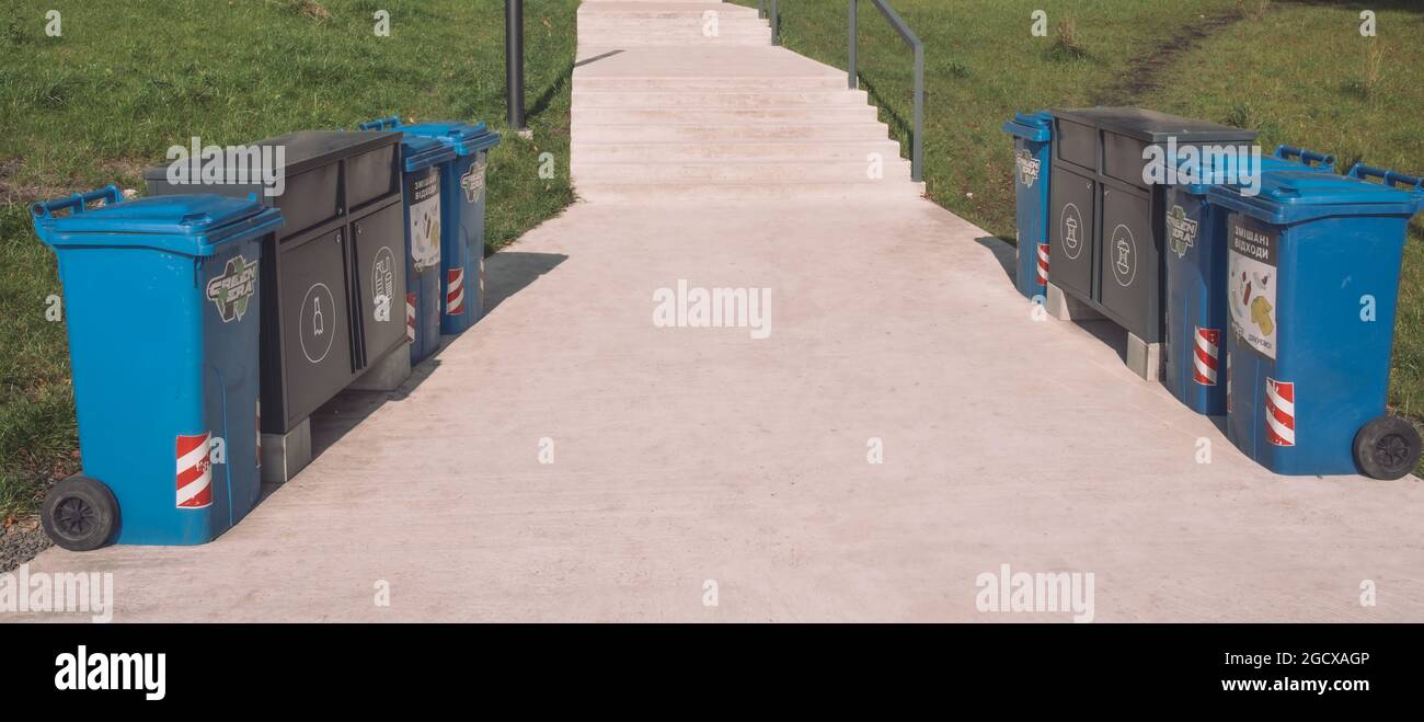 Pavement in park with trash recycling cans for sorted garbage by sides ...