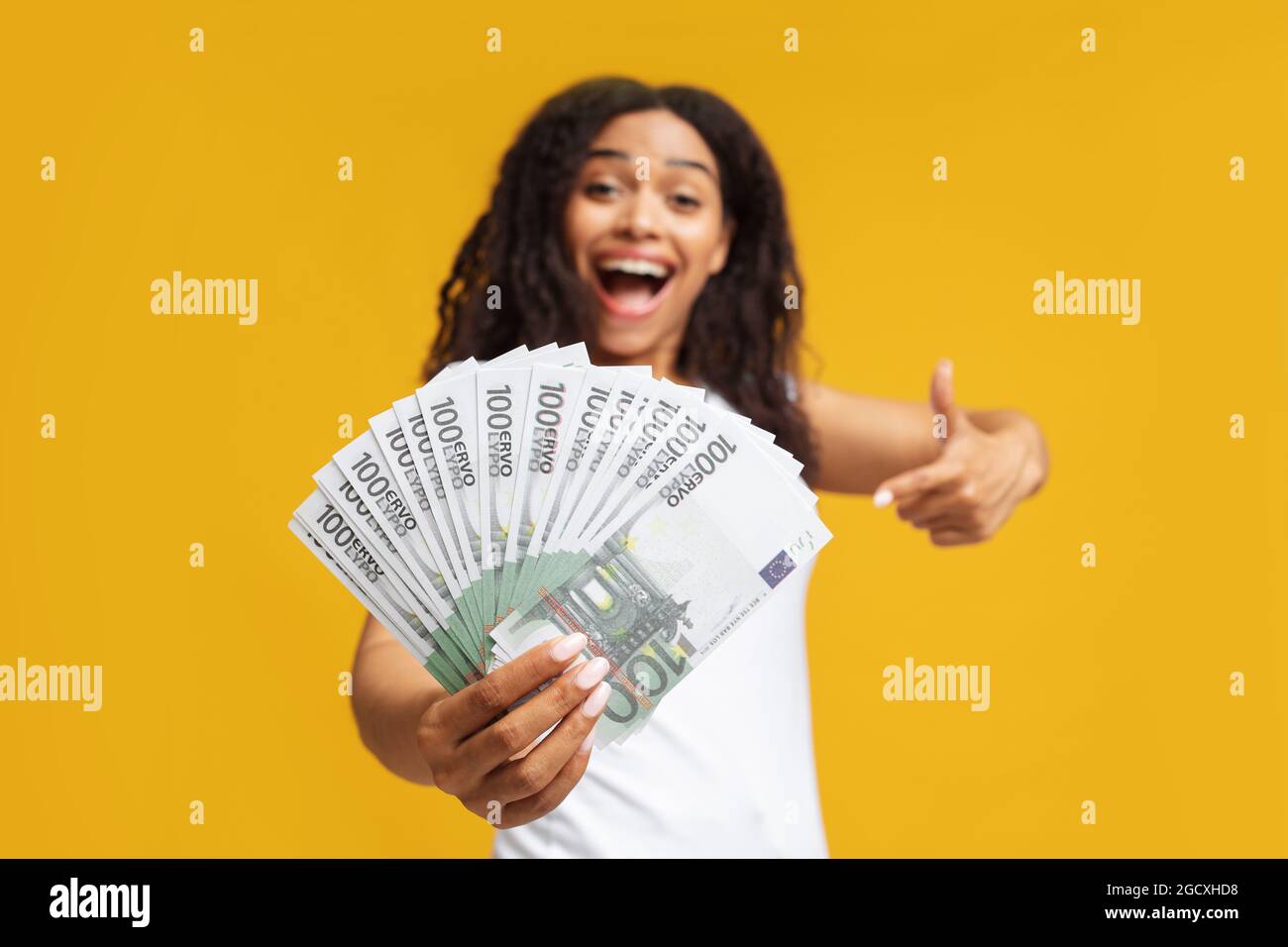 Excited african american woman holding european money cash pointing ...