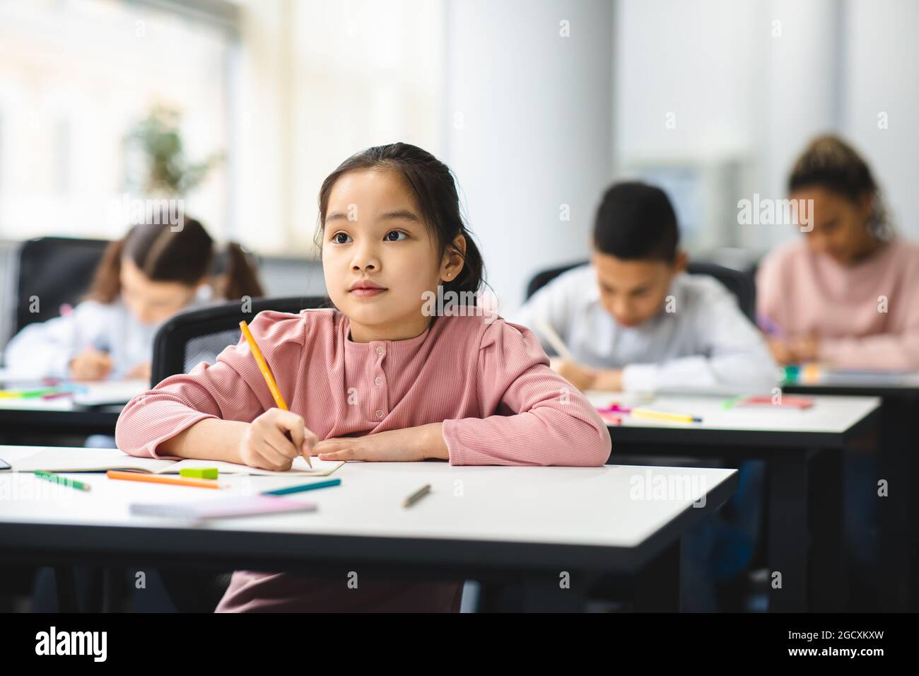 Portrait of asian girl sitting in classroom and writing Stock Photo - Alamy