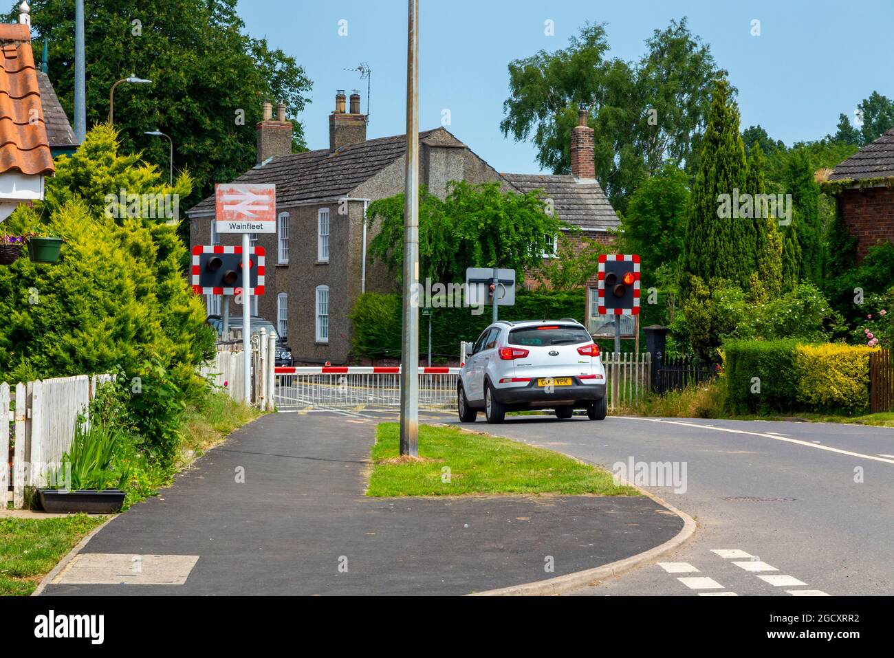 Car and gates at automated level crossing on a railway line at ...