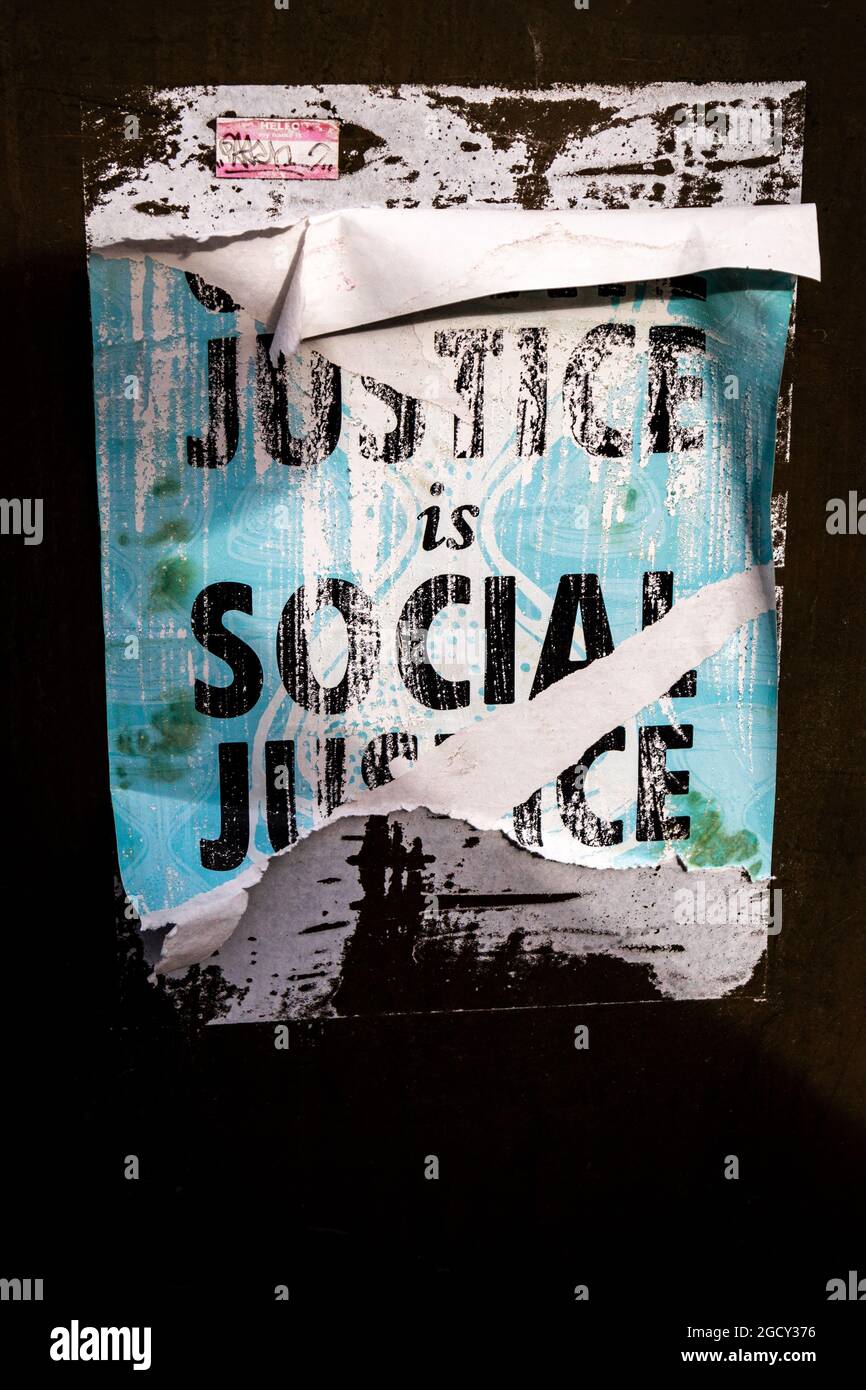 A torn blue Justice is Social Justice poster against a dark background ...