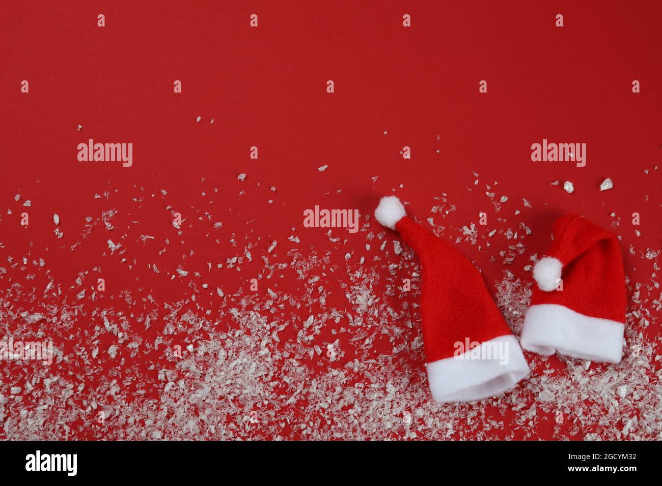 Santa hats and snow on red background Stock Photo - Alamy