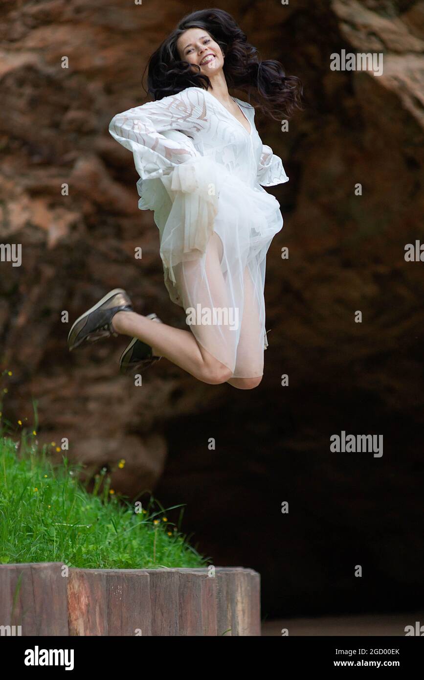funny young woman in white dress jumping from wooden bench Stock Photo ...
