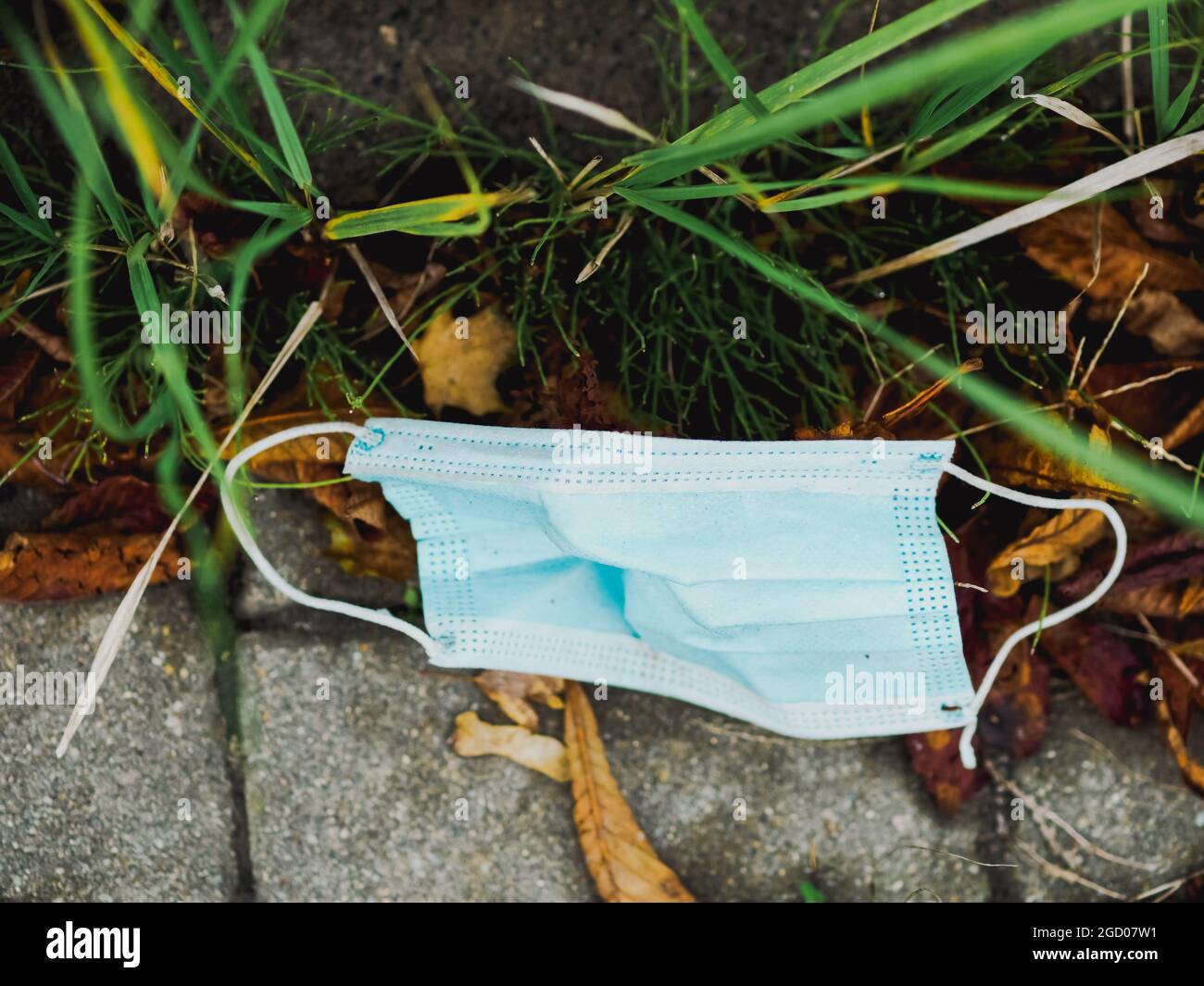 Used medical face mask on the ground outdoor. Environmental pollution ...
