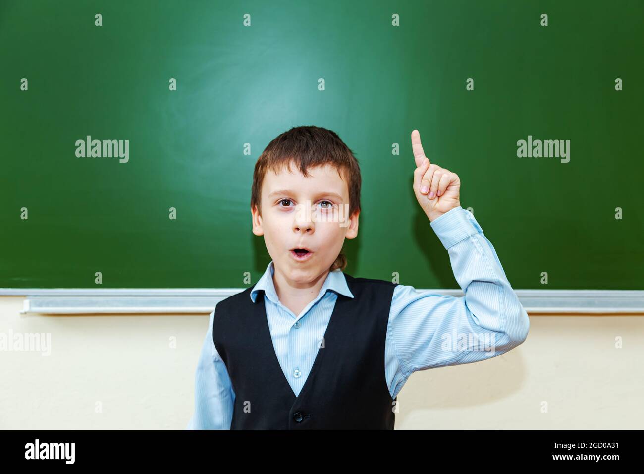 Funny schoolboy near the green school board in the classroom ...