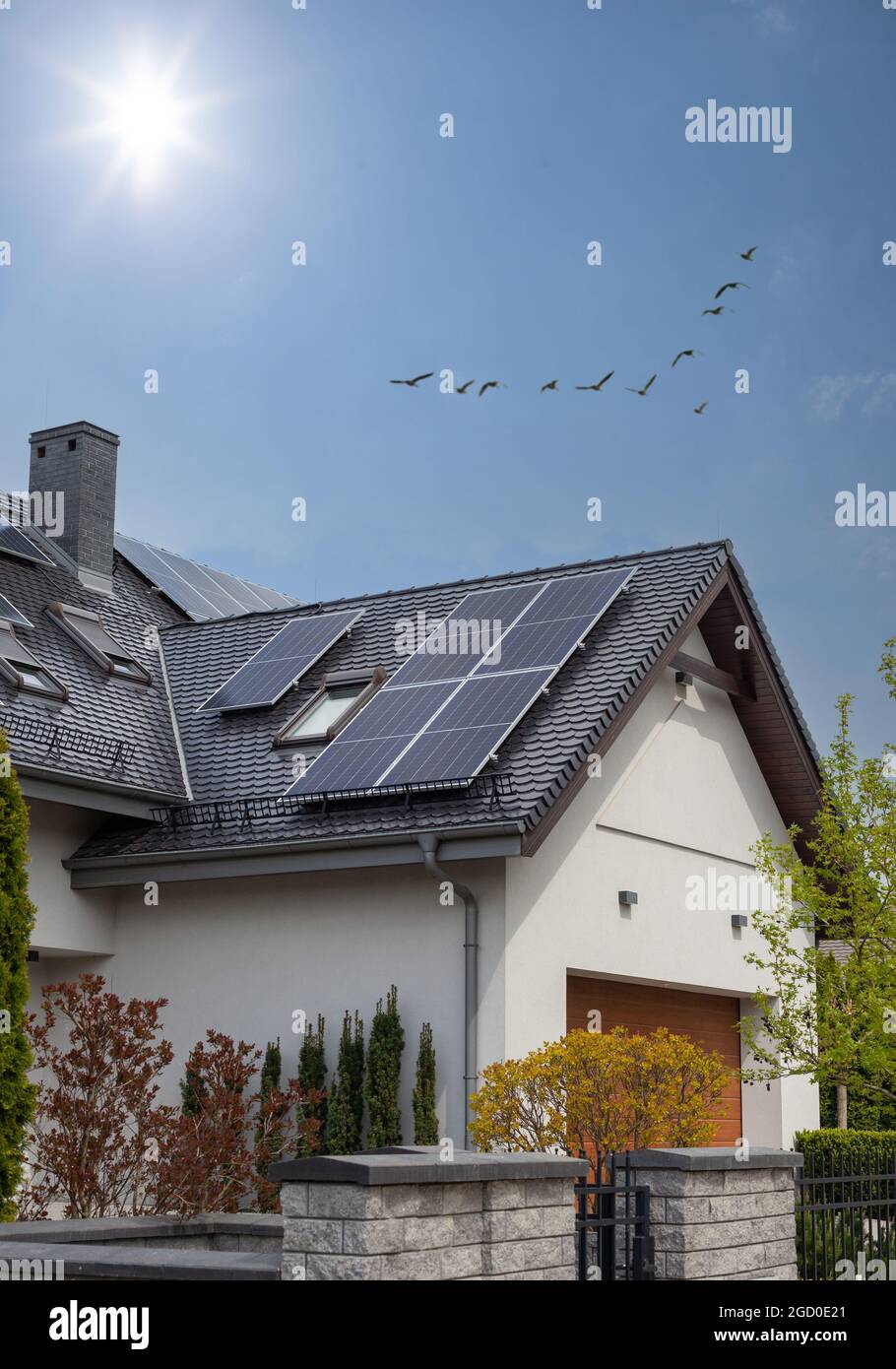 Solar Panel on a dark gable roof - blue sky and sun. Moder house ...