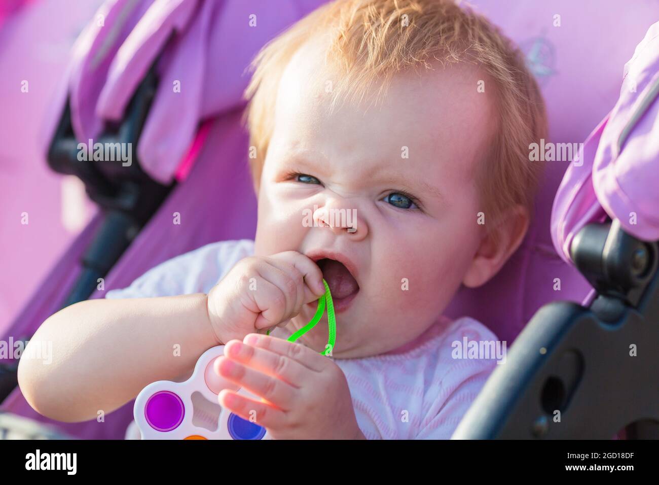 A smiling child nature nibbles a bright colored toy with milk teeth ...