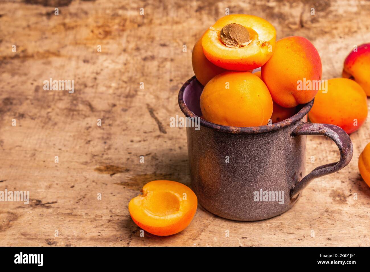 Ripe apricots in a vintage iron mug. Sweet fruits, old wooden table ...