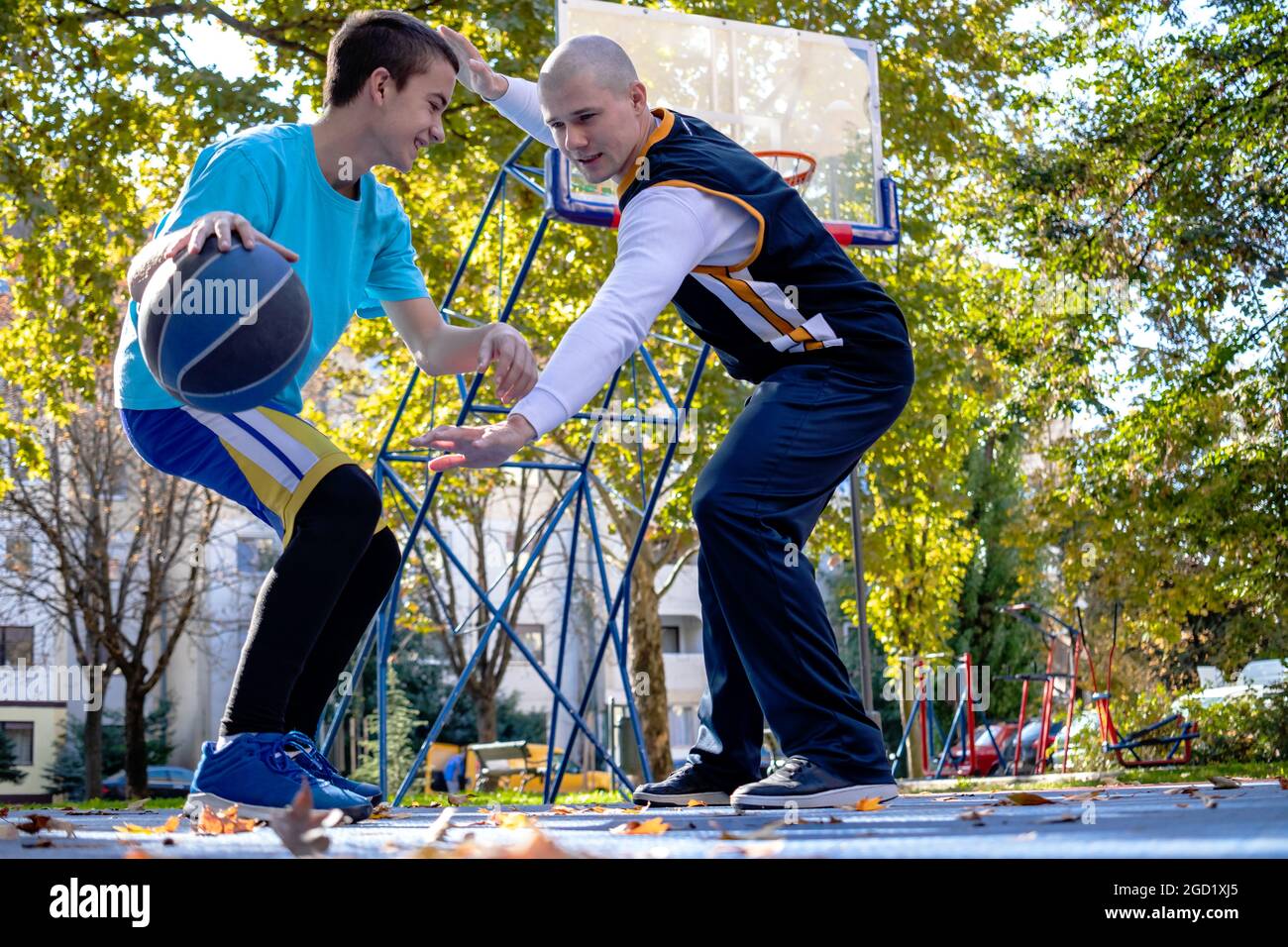 Brothers playing basketball One On One in the open court. Older brother ...