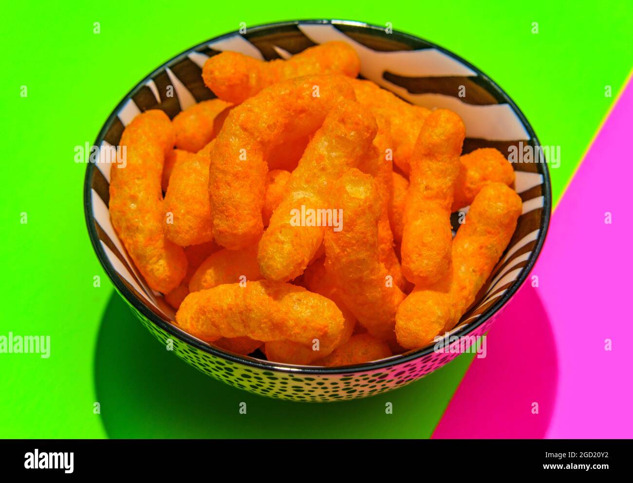 Cheddar cheese flavored puffed corn curls snack on neon colorful ...