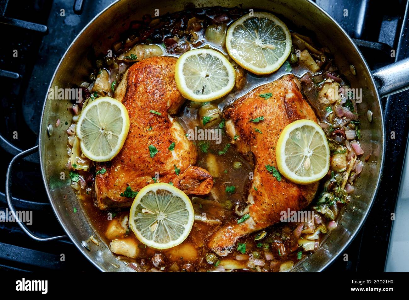 Cooking Italian split chicken leg piccata in large pan on kitchen stove ...