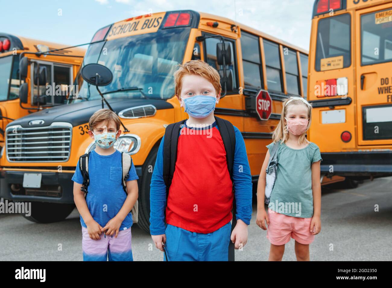 Three children kids students in protective face masks near school ...