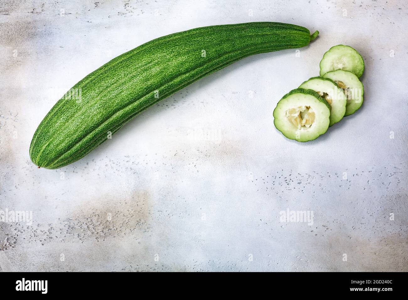 Armenian striped cucumber (Cucumis melo var. flexuosus) atop grey ...