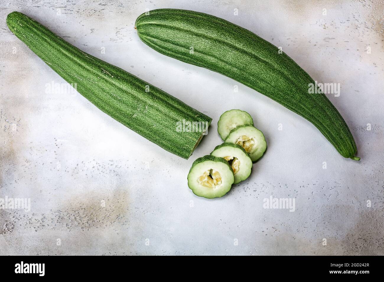 Armenian striped cucumber (Cucumis melo var. flexuosus) atop grey ...