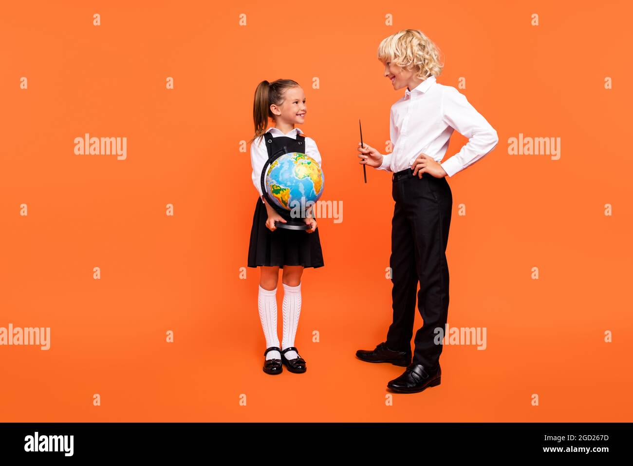 Photo of cheerful schoolchildren hold globe pointer prepare homework ...