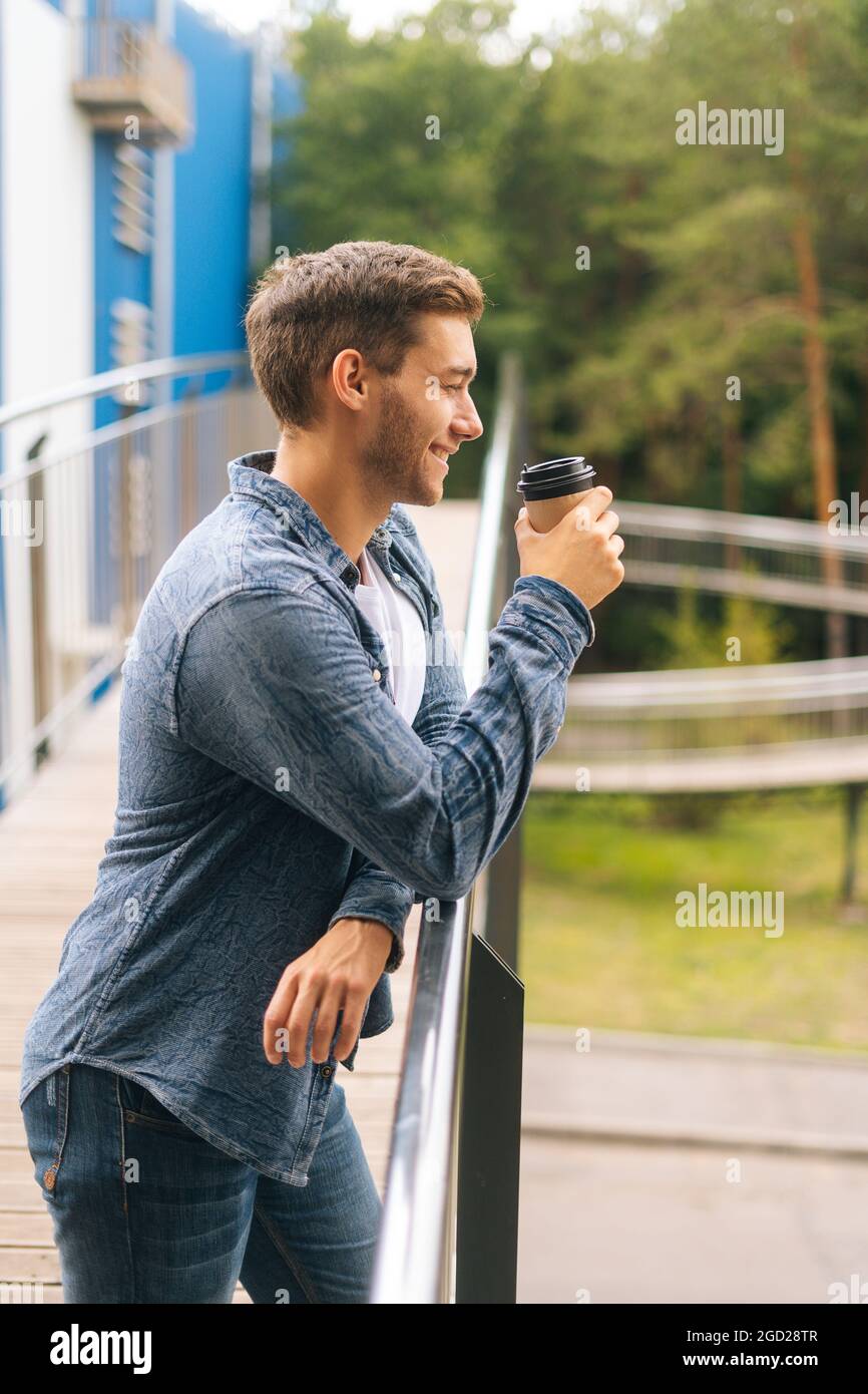 Side view of confident thoughtful young man standing on balcony terrace ...