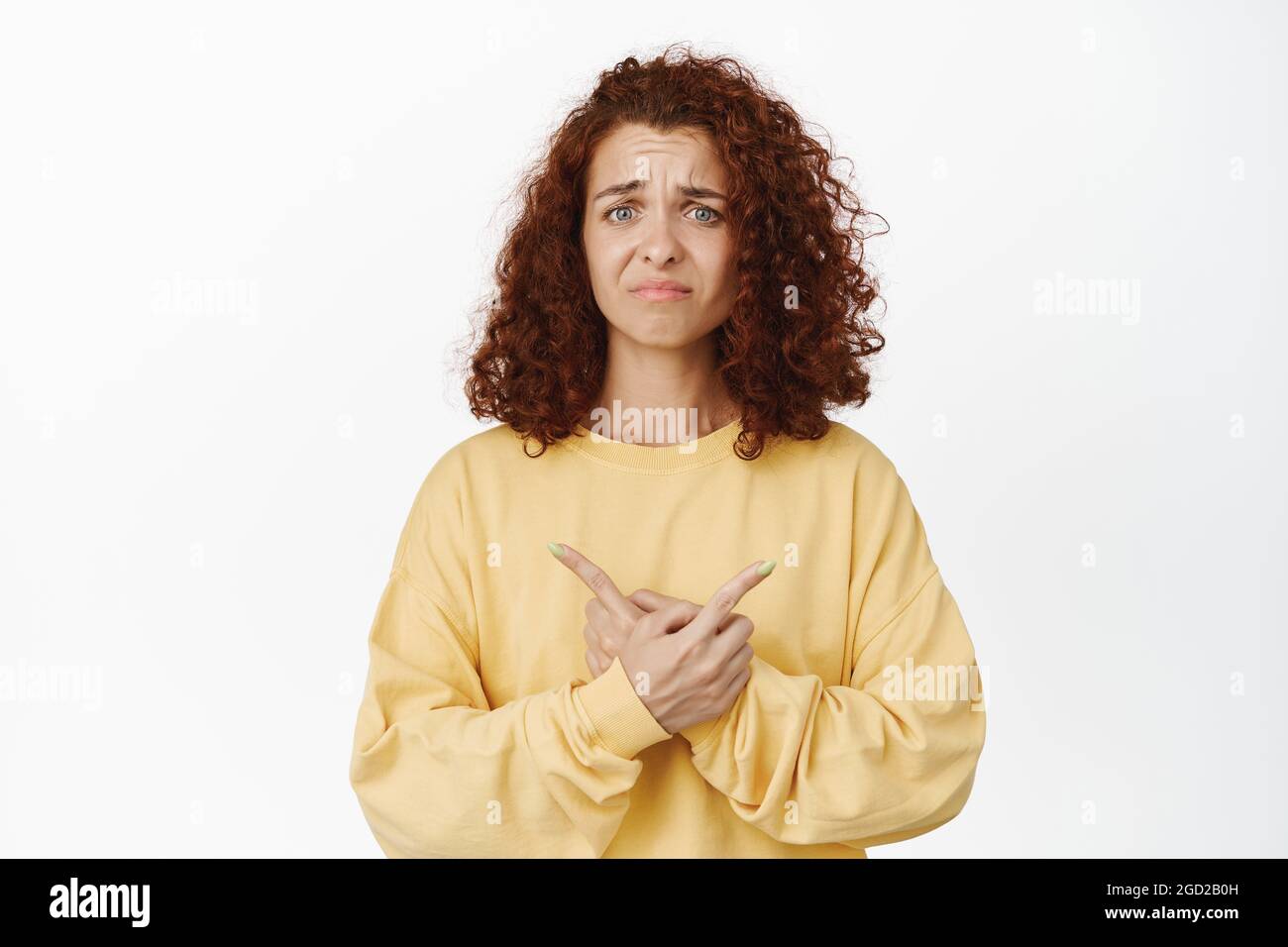 Confused sad girl pointing fingers sideways, points left and right and ...
