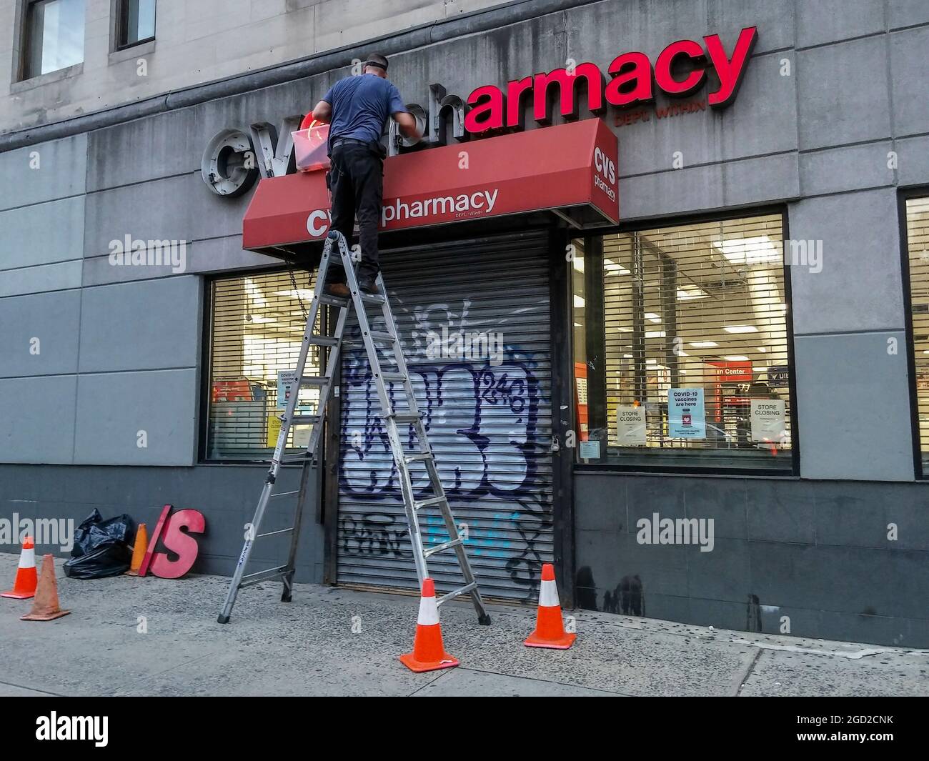 A worker removes the signage from a closed store in the CVS Health drugstore chain in Chelsea in ...