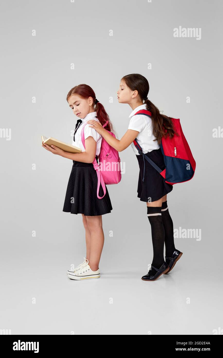 two little cheerful friends schoolgirls with backpacks read book Stock ...