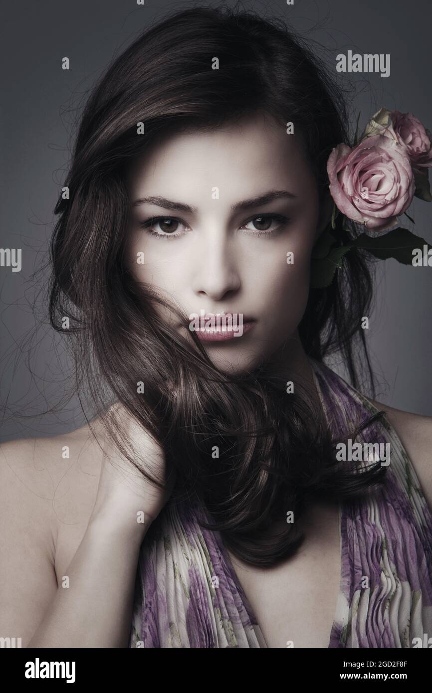 Beautiful young woman with a pink rose in hair Stock Photo - Alamy