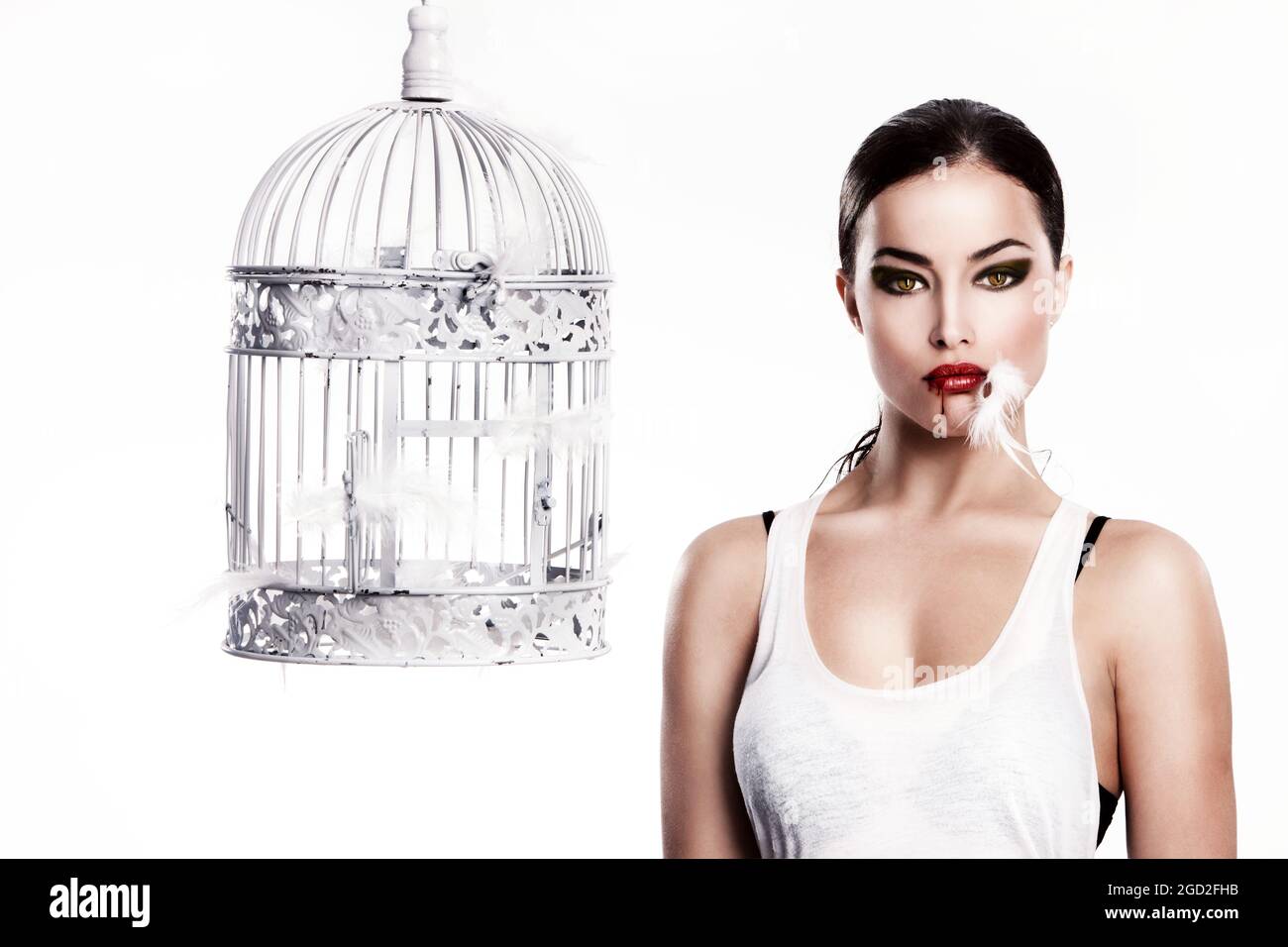 Attractive young woman with white feathers in her hands and mouth stand ...