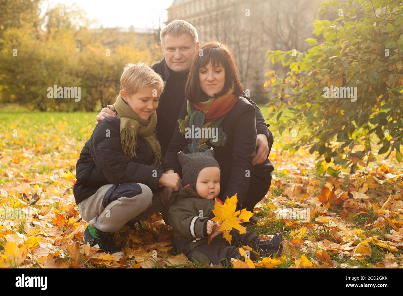 Autumn family sitting on fall leaves in fall park outdoors. Love care ...