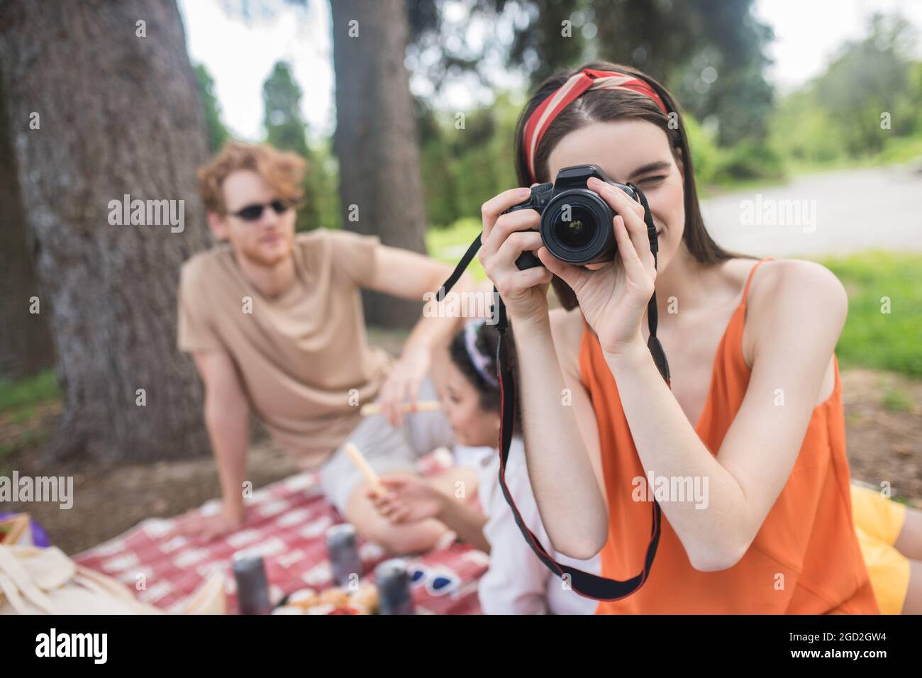 Girl looking into camera lens and friends behind Stock Photo - Alamy