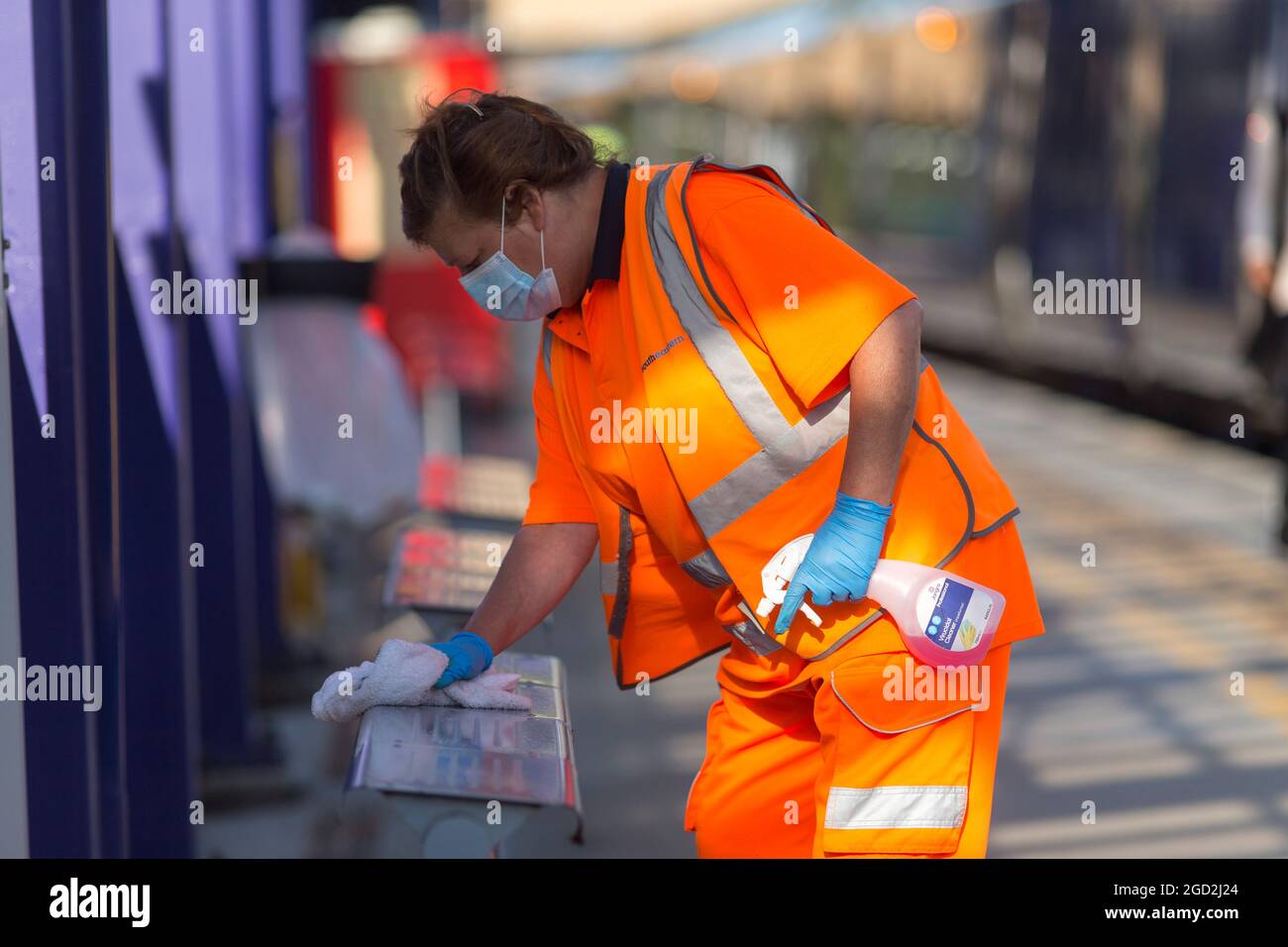 A station cleaner at work disinfecting seats on a platform on the ...