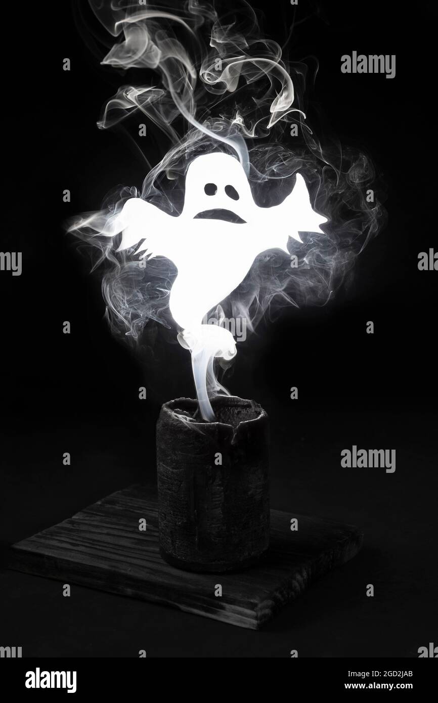 Ghost in smoke from candle on black background, frightening restless ...