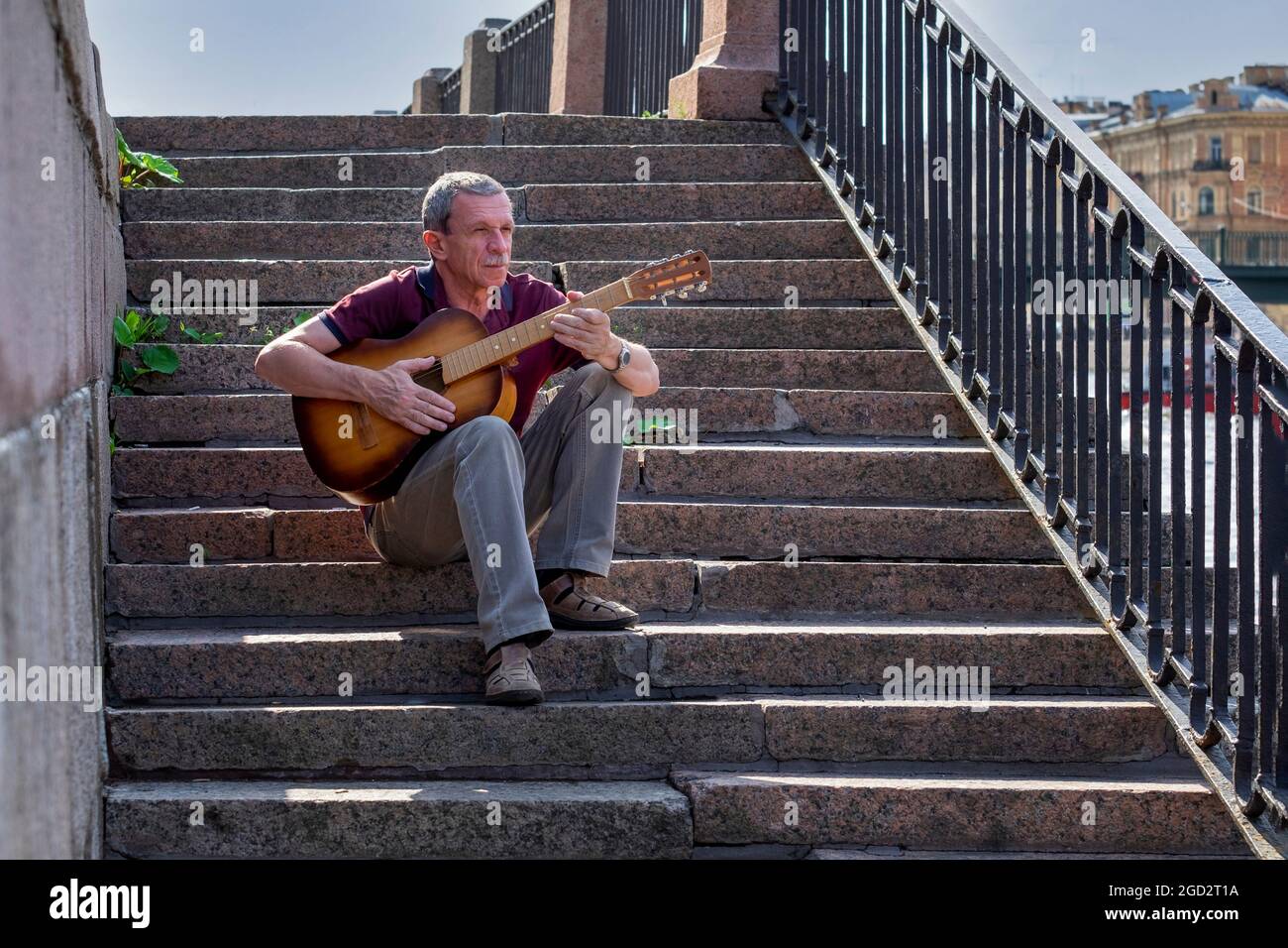 An adult elderly man of retirement age plays an old six-string ...