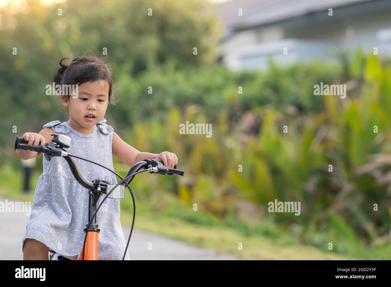 Cute little Thai girl riding a bicycle Stock Photo - Alamy