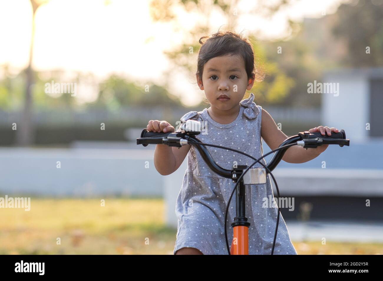 Cute little Thai girl riding a bicycle Stock Photo - Alamy