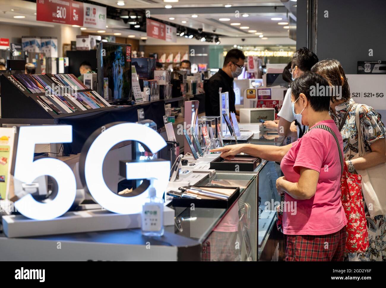 Shoppers are seen at an electronic store displaying mobile phone brands ...