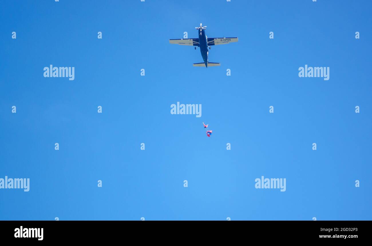 looking up at a parachute jumper egressing a light aircraft flying ...