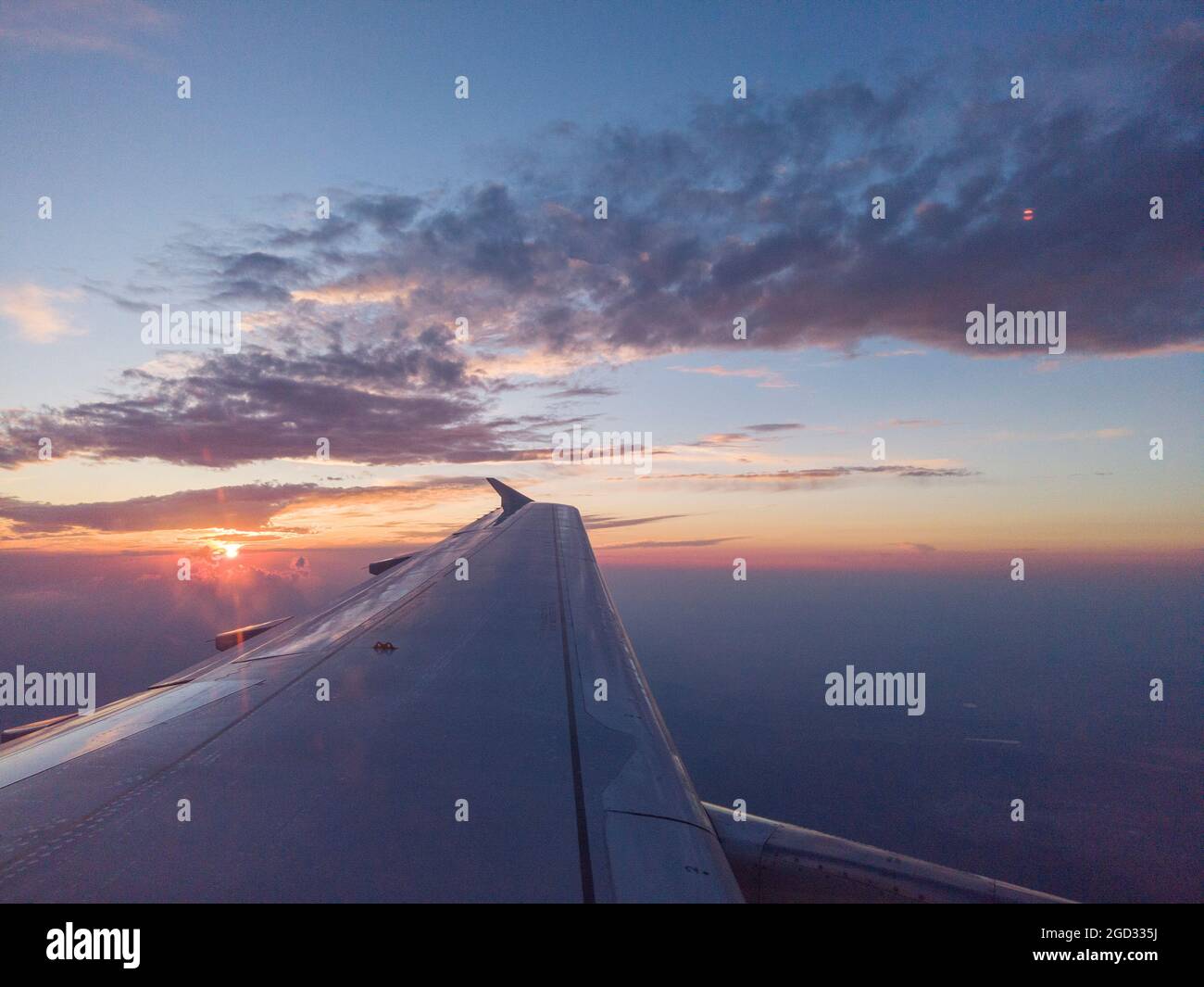 SUNSET ABOVE THE SKY VIEWED INFLIGHT FROM AN AIRPLANE WINDOW WITH THE ...