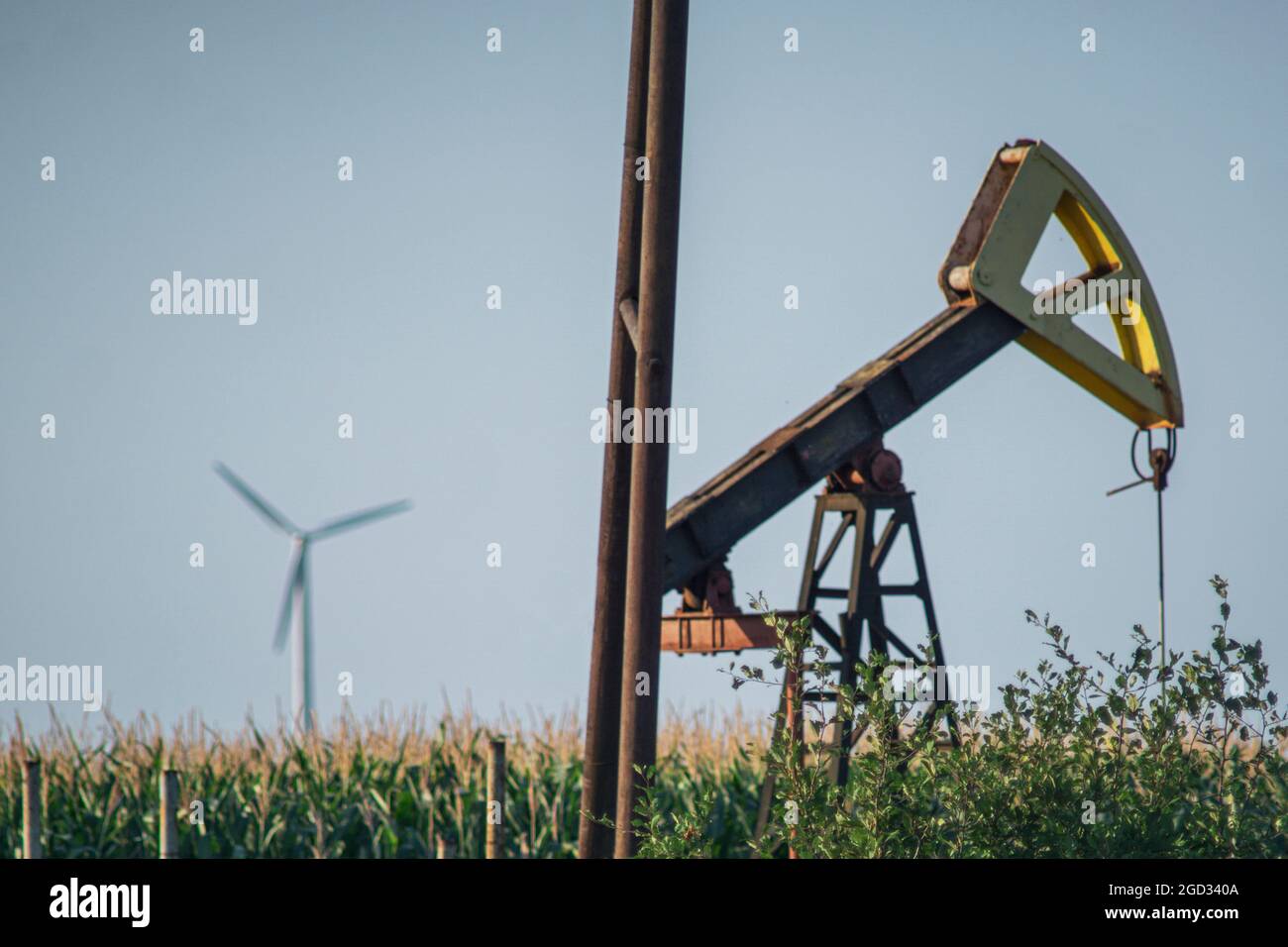 OIL PUMP VERSUS WIND TURBINE IN THE BACKGROUND. CONCEPT: GREEN ENERGY ...