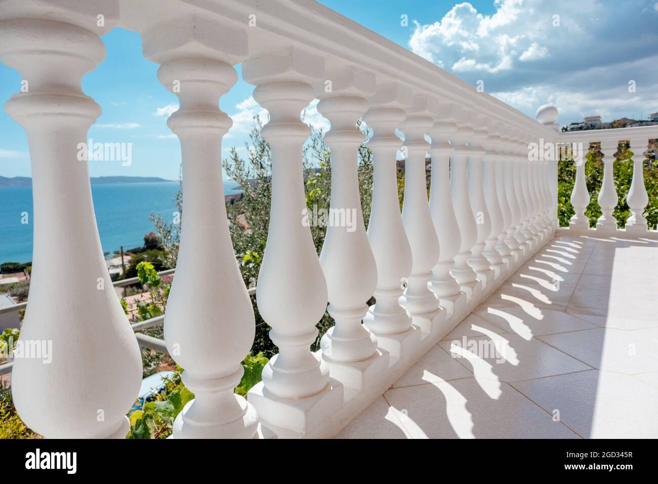 View through balcony on clear blue Aegean sea coast. Traditional white ...