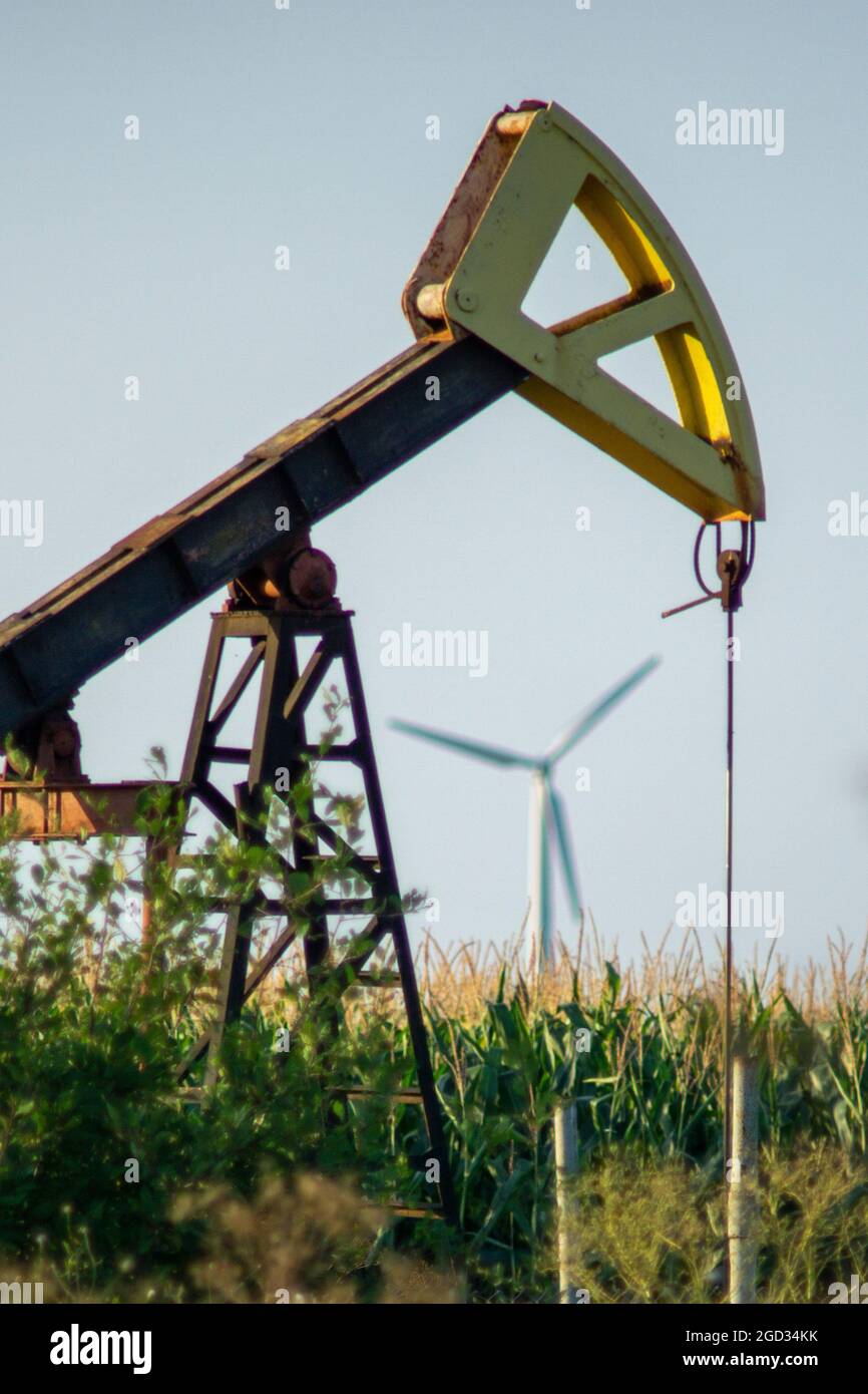 OIL PUMP VERSUS WIND TURBINE IN THE BACKGROUND. CONCEPT: GREEN ENERGY ...