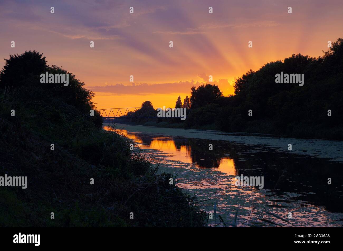 A stunning sunset with sun rays of light across the sky and reflections ...