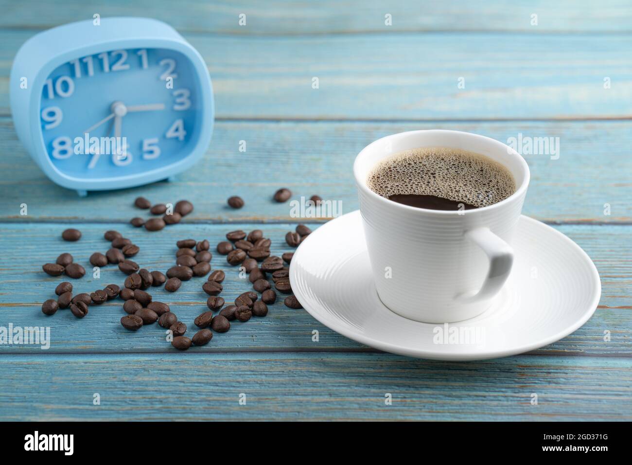 Cup of coffee and a blue alarm clock on a table Stock Photo - Alamy