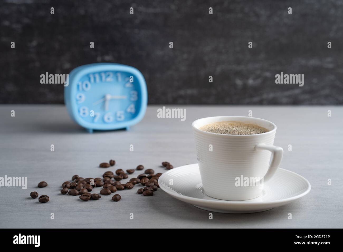 Cup of coffee and a blue alarm clock on a white table Stock Photo - Alamy