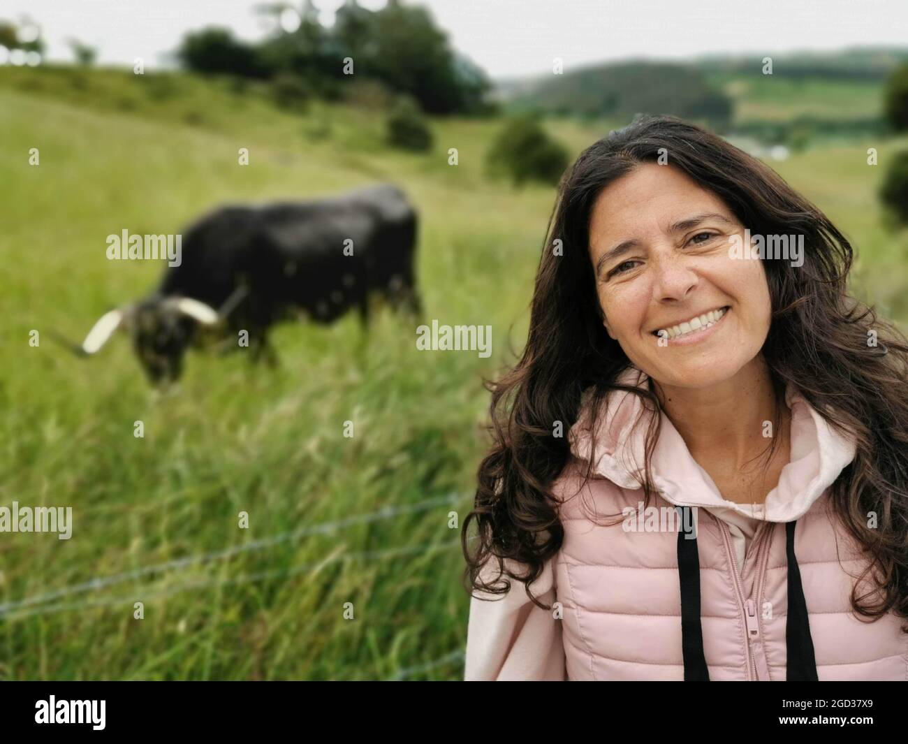 Portrait of a female standing in nature and an ox in a background Stock ...