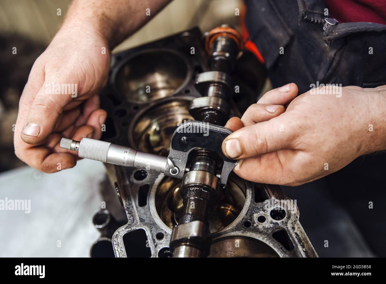 a measuring device in hand measures the camshaft against the background ...