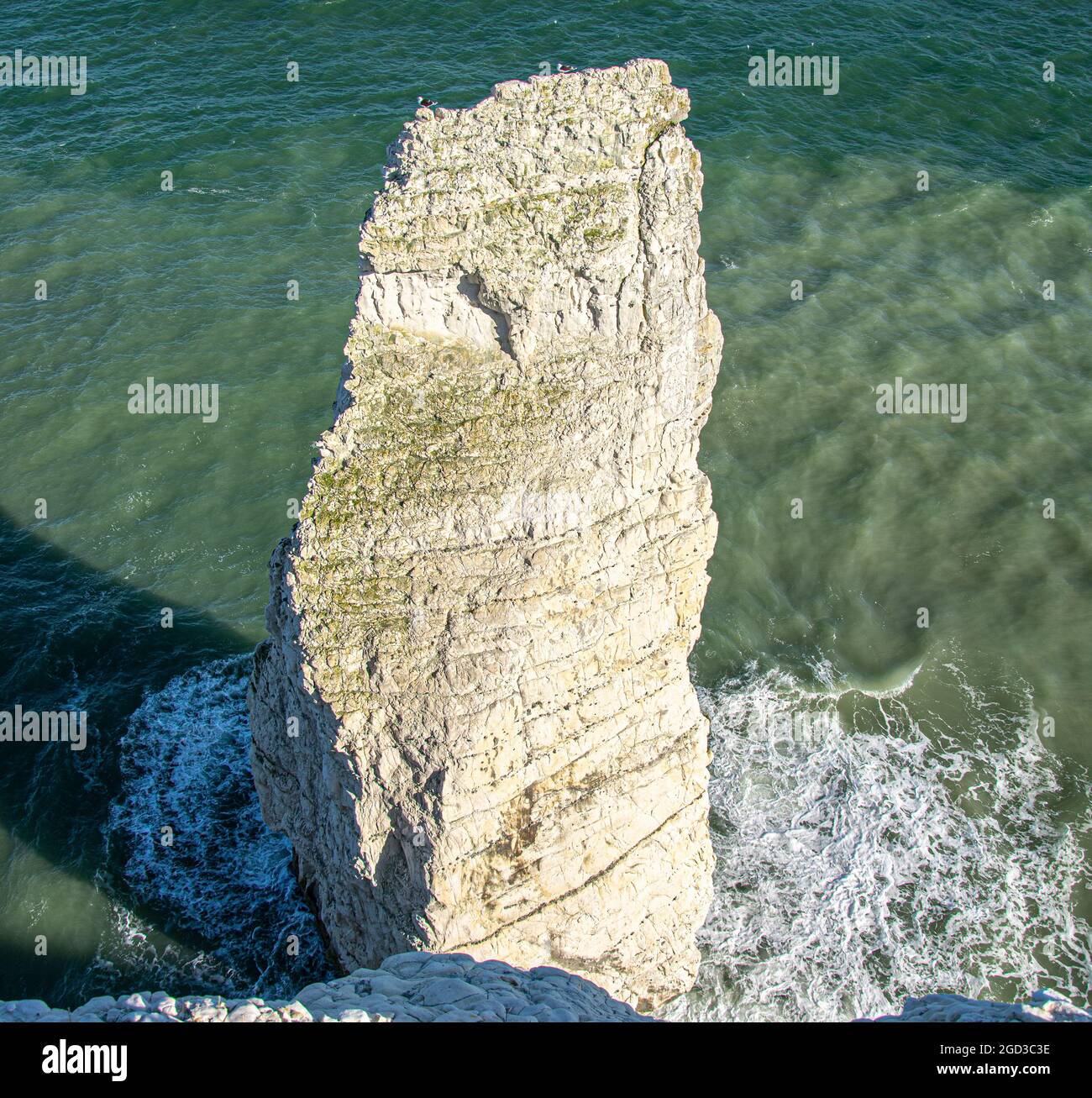 Beautiful aerial shot of a tall cliff sticking out of the green-blue ...